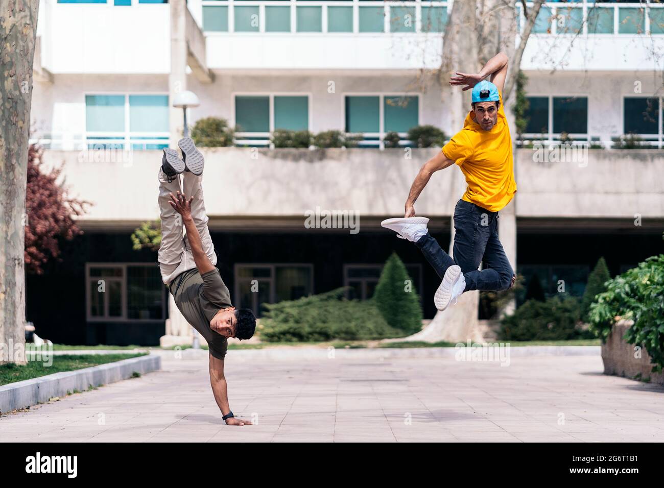 Two multi-ethnic friends dancing in the park and doing break dance ...