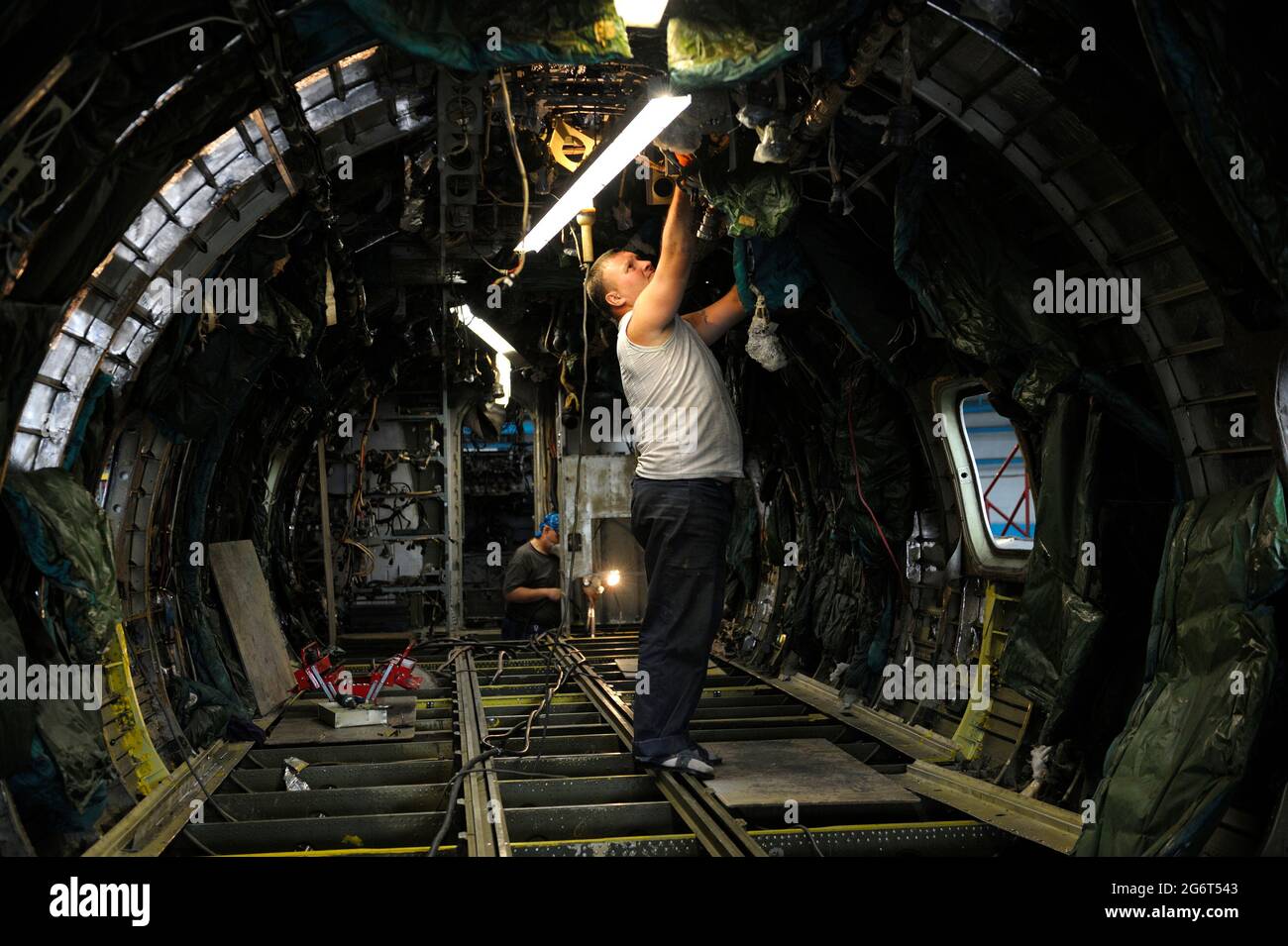Worker installing electric wiring inside of a body plane. The State ...