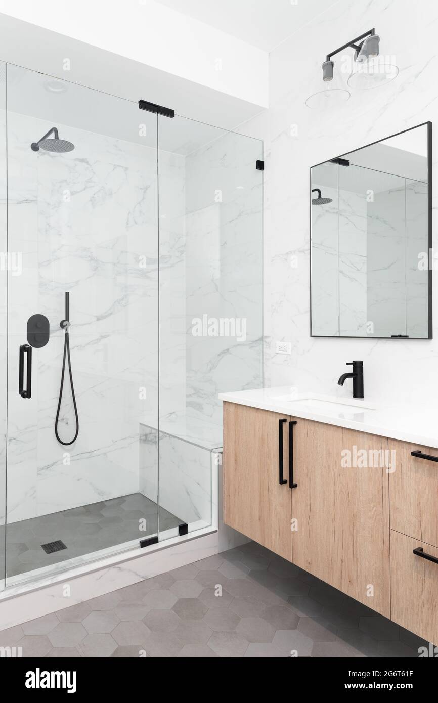 A beautiful luxury, modern bathroom with a light wood cabinet, walk-in ...