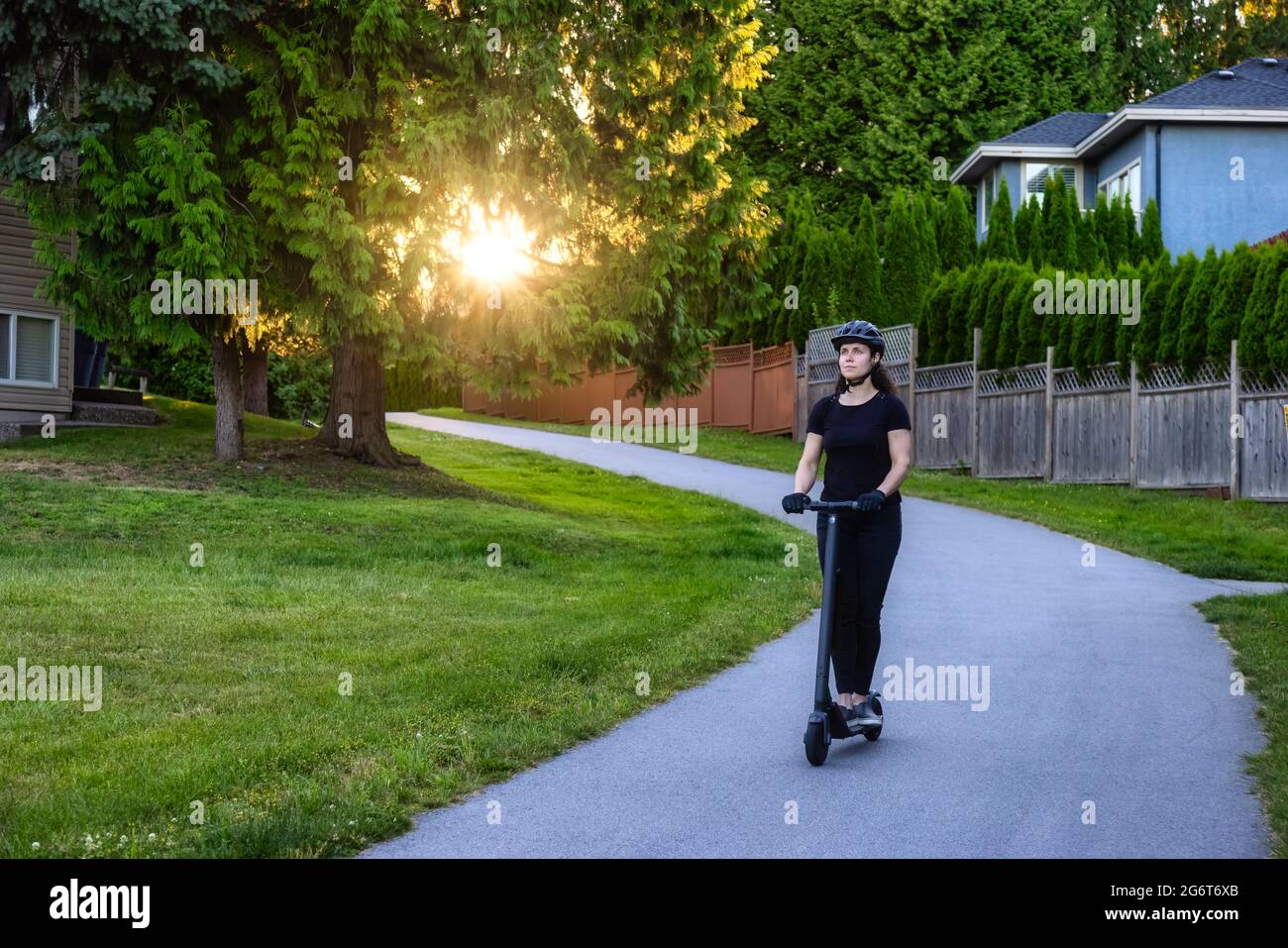 Caucasian Adult Woman riding an electric scooter on a path Stock Photo ...