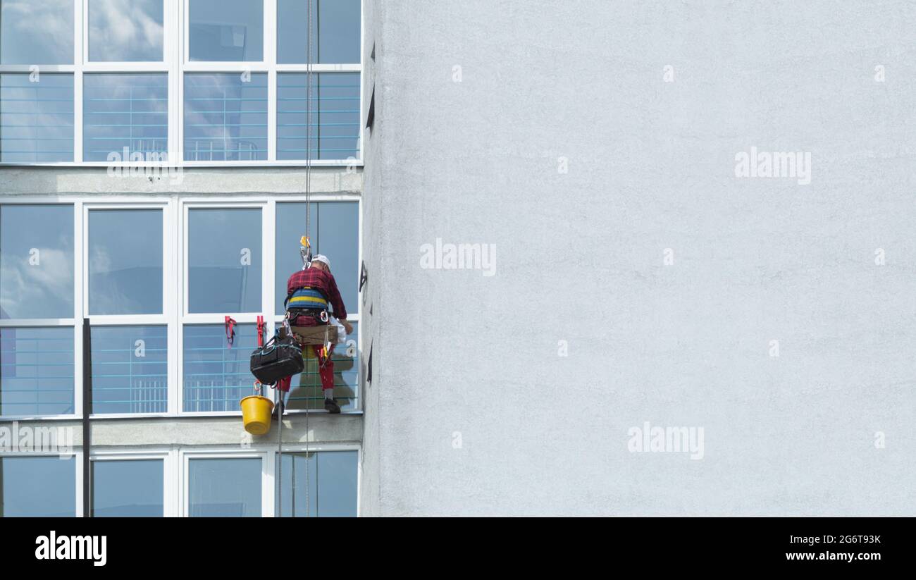 A man washes windows in a multi-storey building. Professional window ...