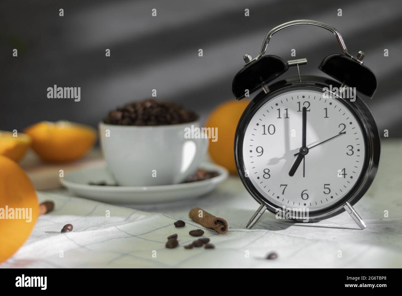 The retro alarm clock indicates 7:00 am and is illuminated by rays of ...
