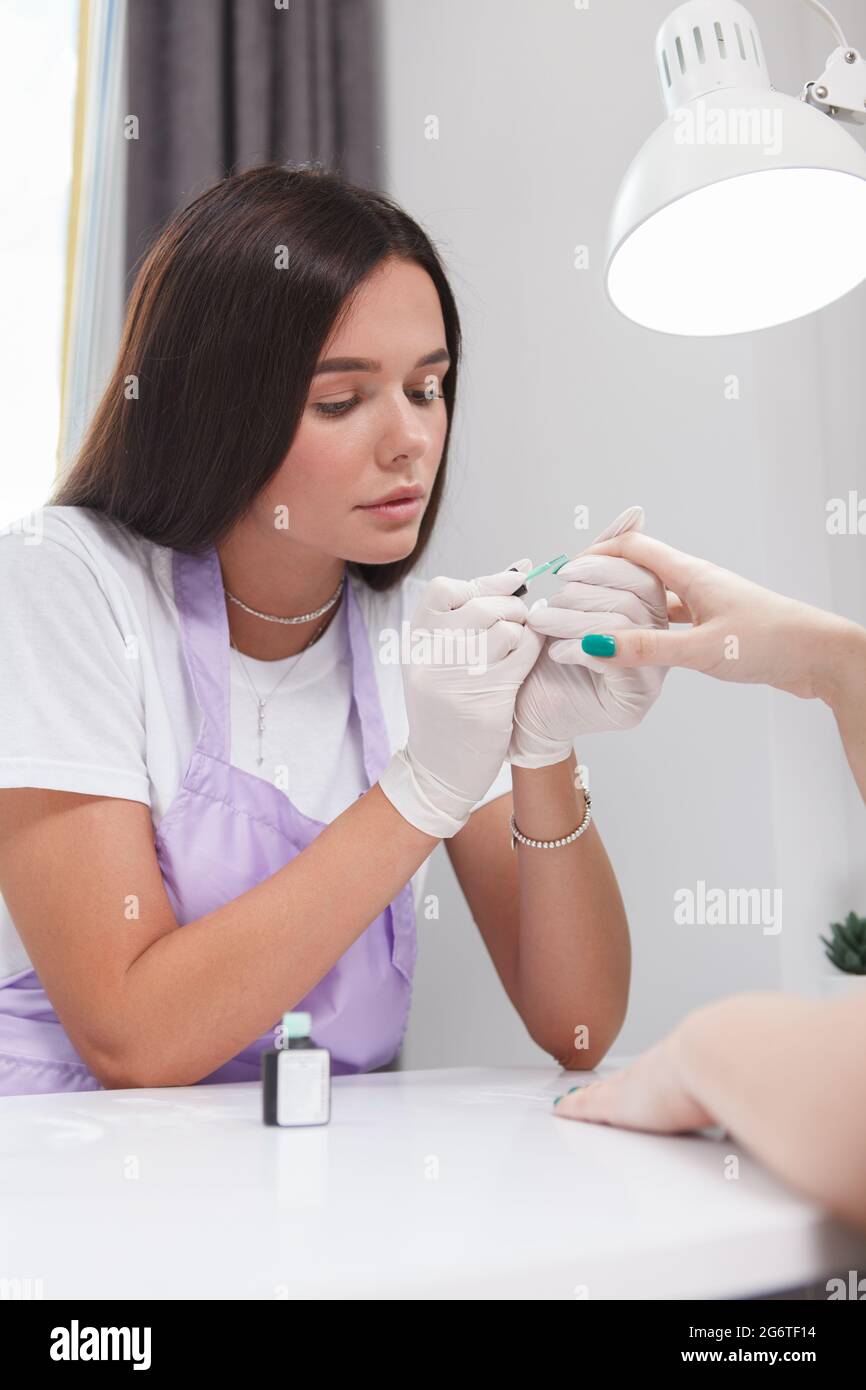 Vertical shot of a professional manicurist using nail drill on clients ...