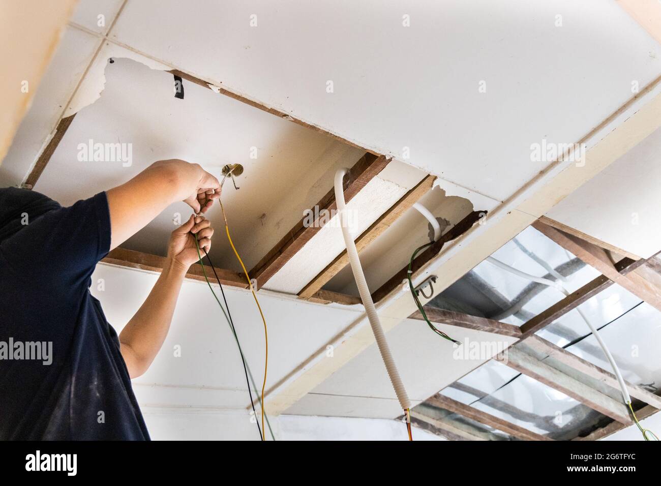 Electrician concealing electicity power wire lines within plastic tube ...