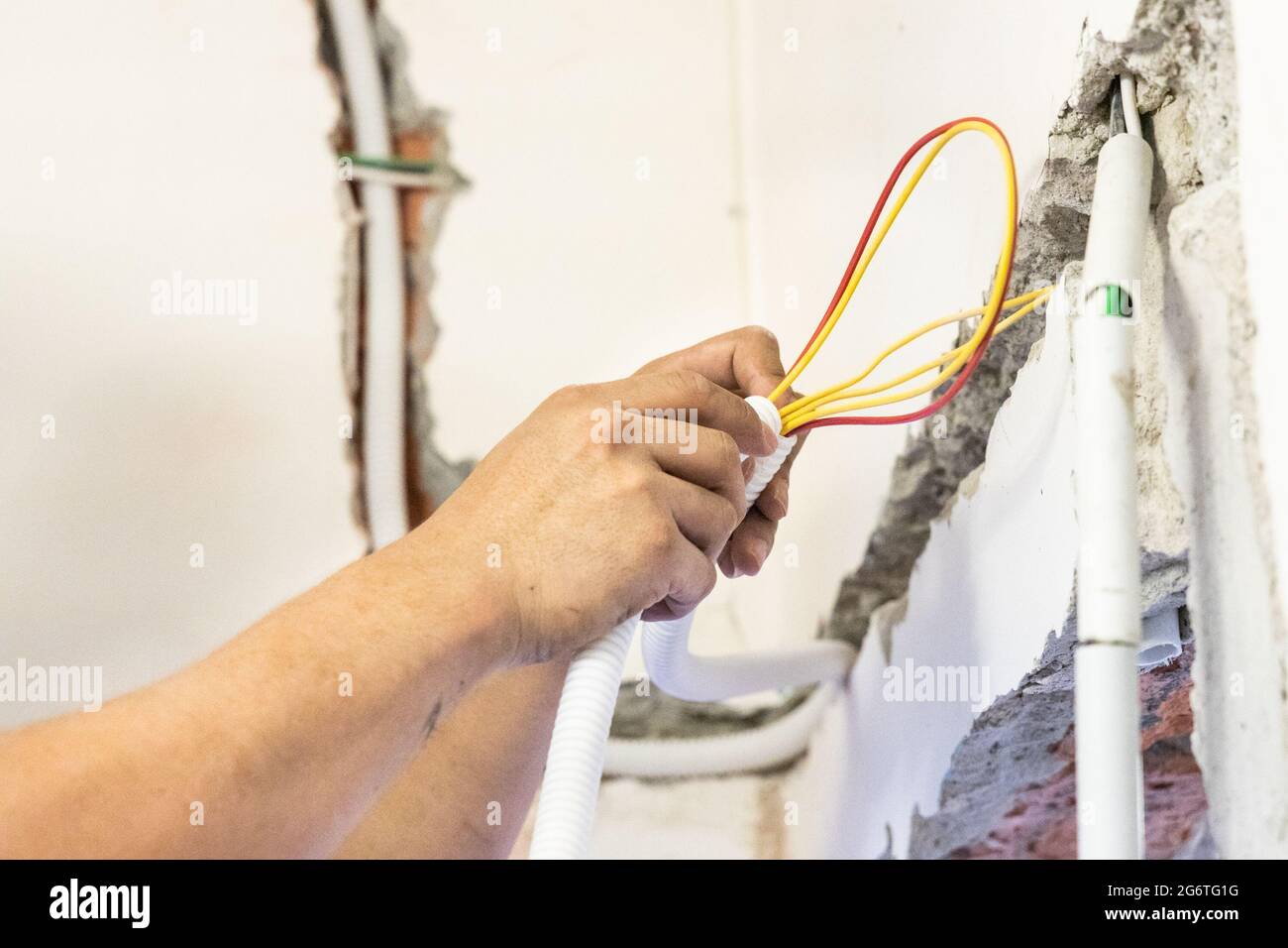 Electrician concealing electicity power wire lines within plastic tube ...