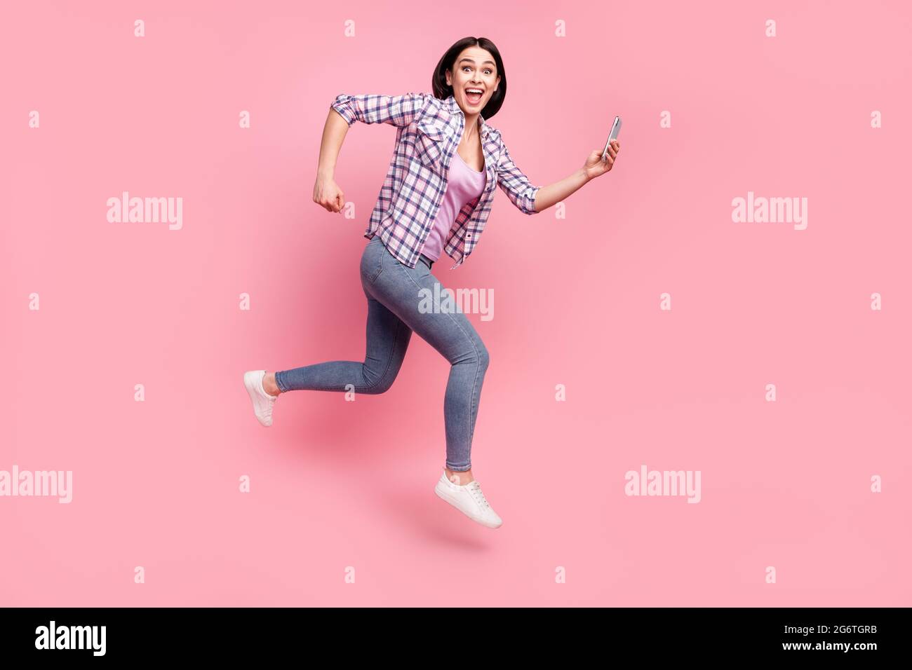 Photo of shiny funky young lady dressed plaid shirt smiling jumping ...