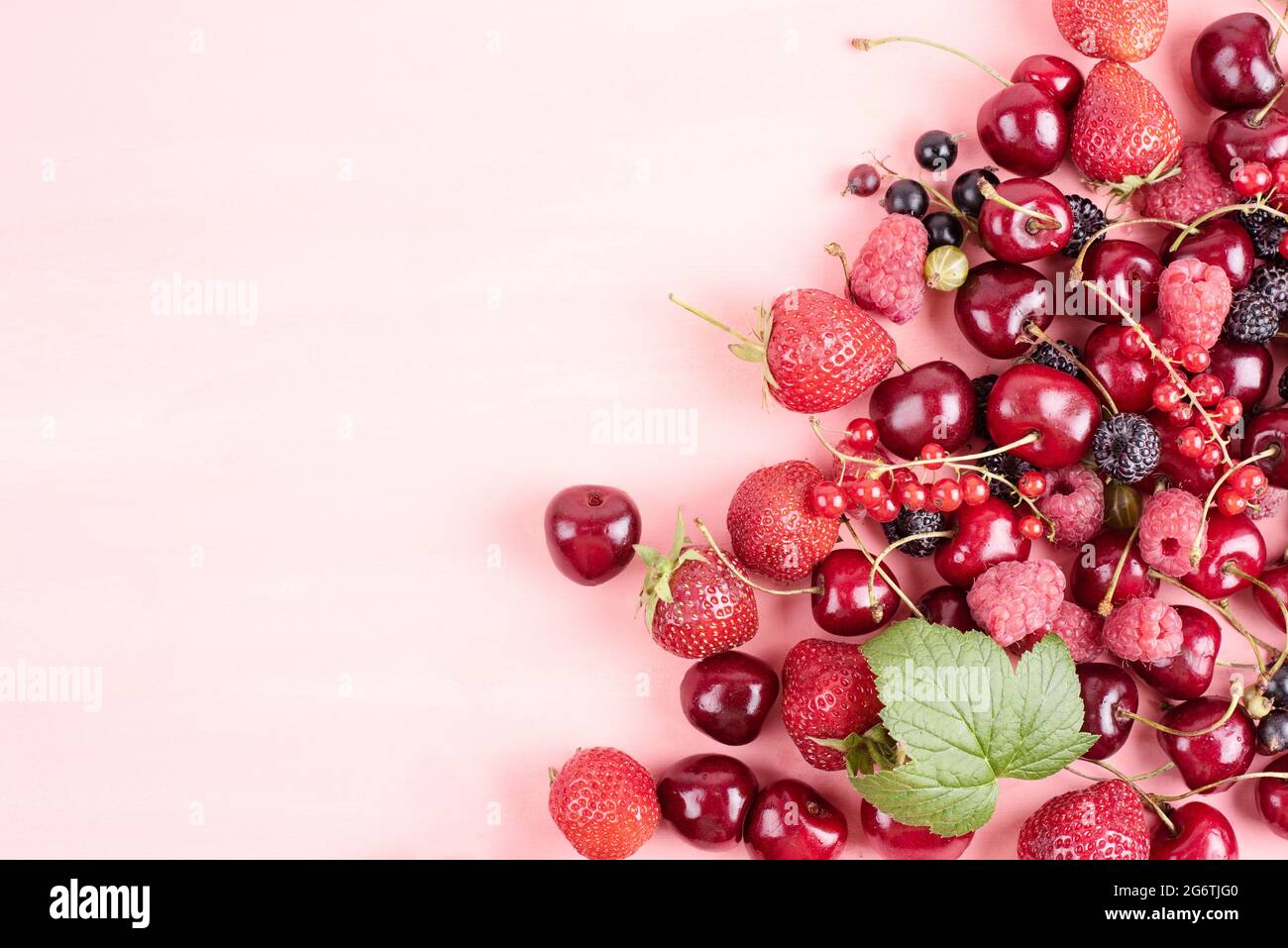 Pink background with various summer berries strawberries, raspberries ...