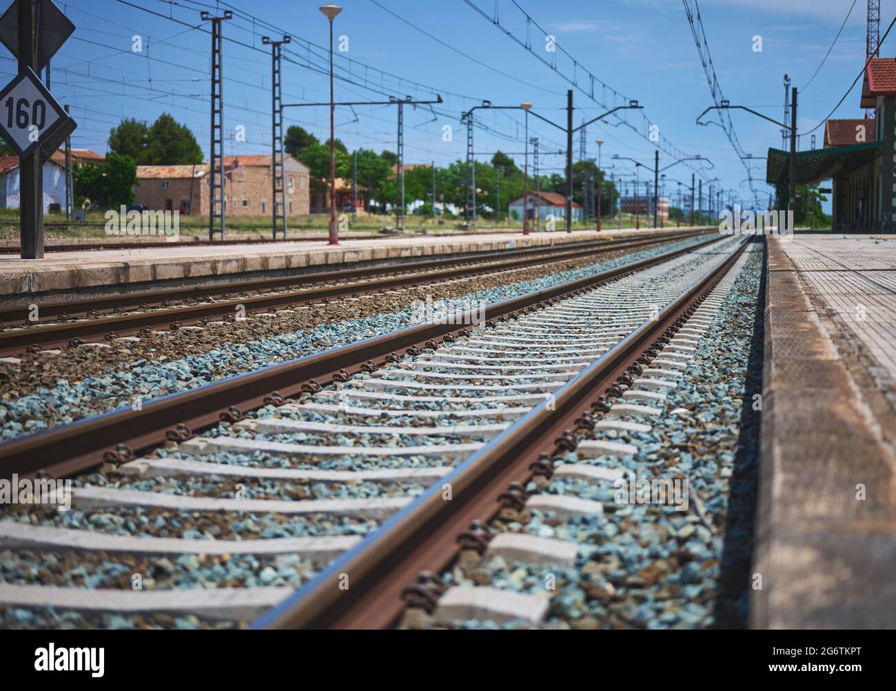 detail of a train station with the platform, tracks and catenary by day ...
