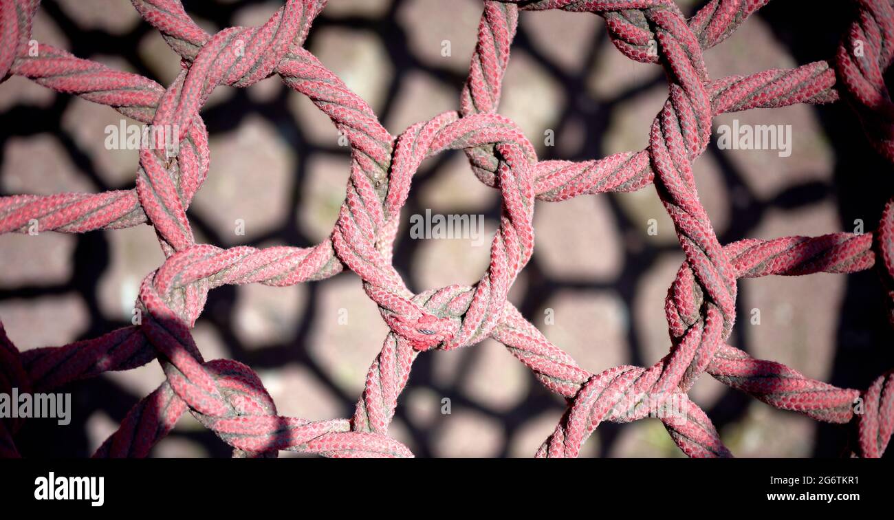 detail of a red and dirty sand net on a sandy ground with shadow cast ...