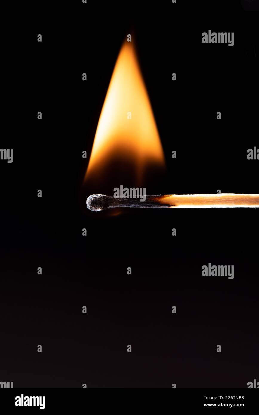 Triangular flame of fire on a match over a black background. Burning ...