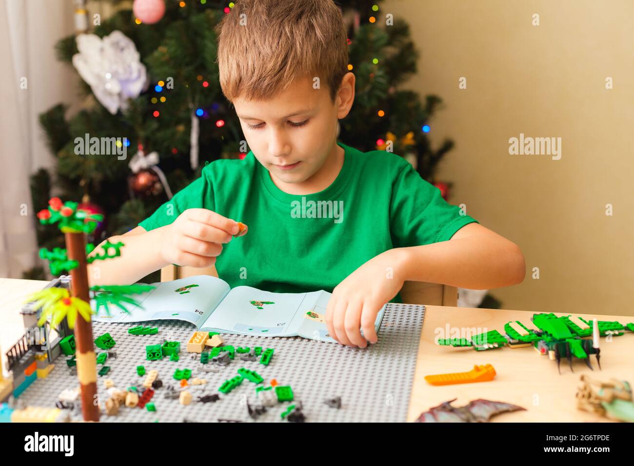 Cute boy collecting block constructor according to instructions sitting ...