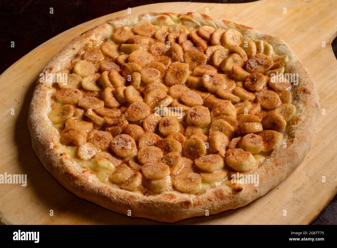 Banana pizza with sugar and cinnamon on wooden board. Brazilian sweet ...