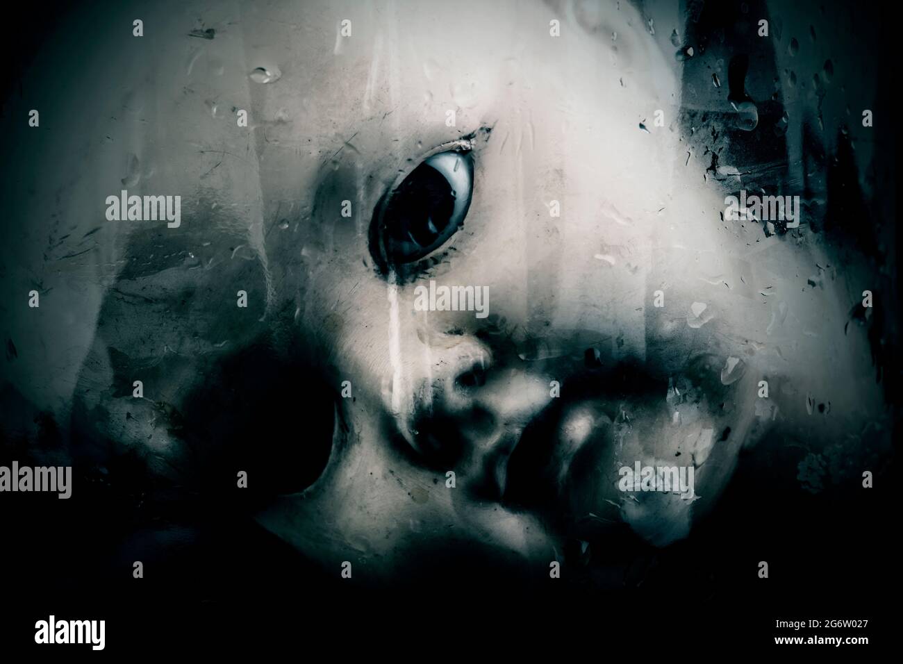 Creepy doll face behind the old glass Stock Photo - Alamy