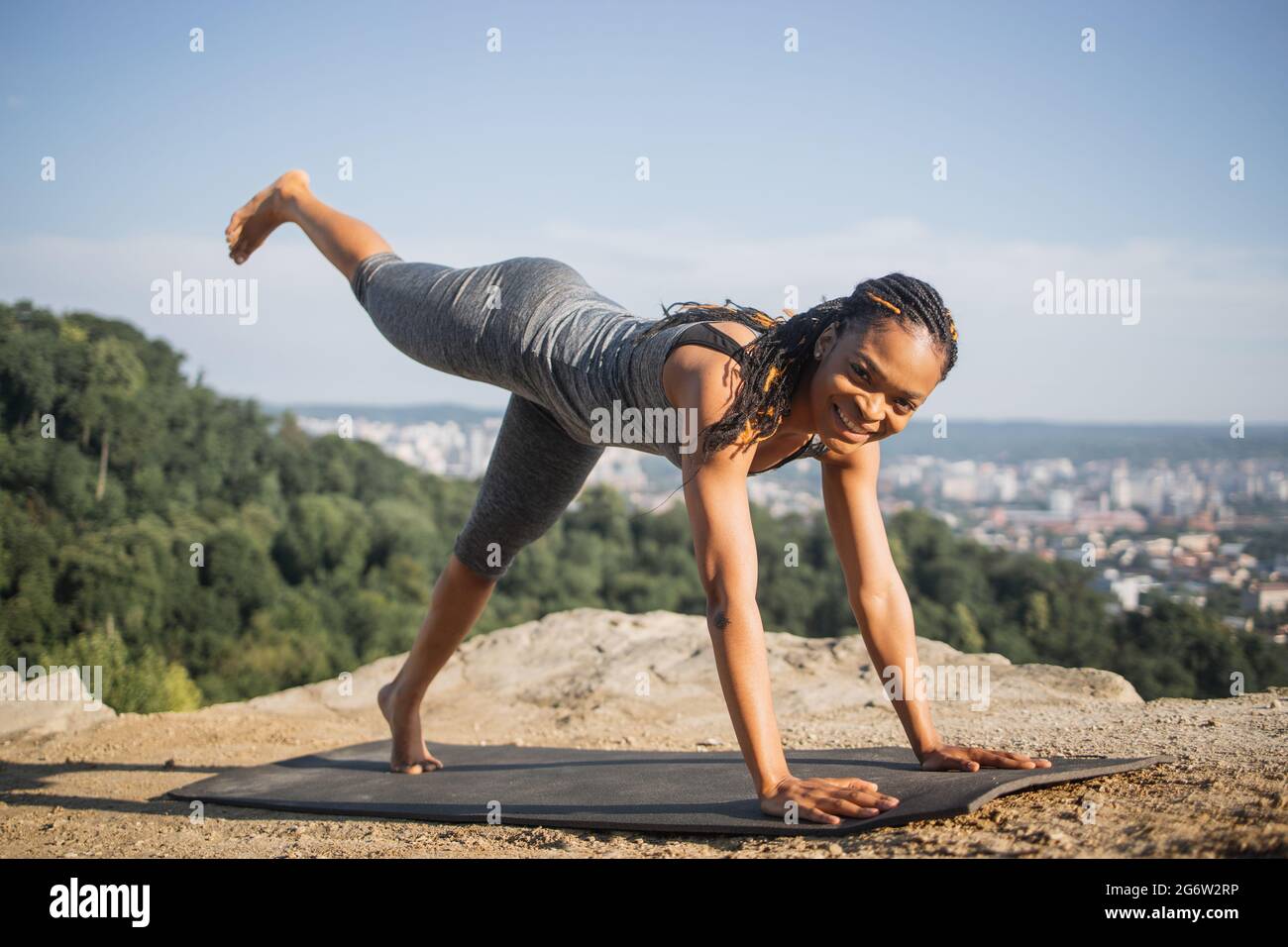Positive african woman in sport clothes doing morning exercise on yoga ...