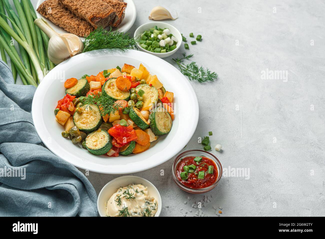 A plate of vegetables on a gray background with herbs and sauces. Side view, space for copying ...