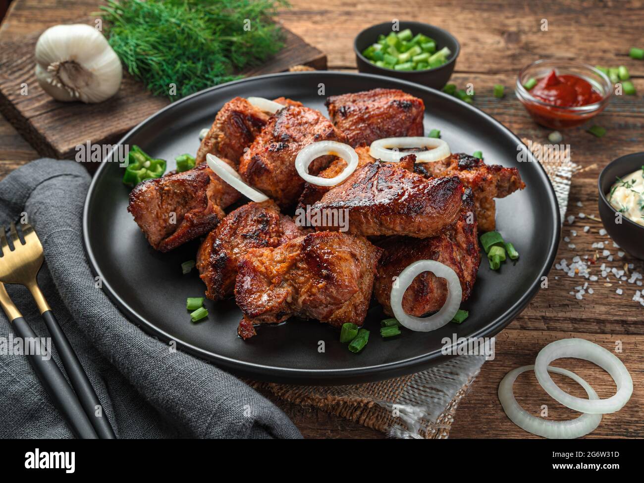 Grilled meat, barbecue, kebab with fresh herbs on a wooden background ...