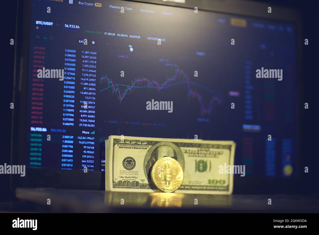 One bitcoin coin and a bundle of one hundred dollar bills, the laptop ...