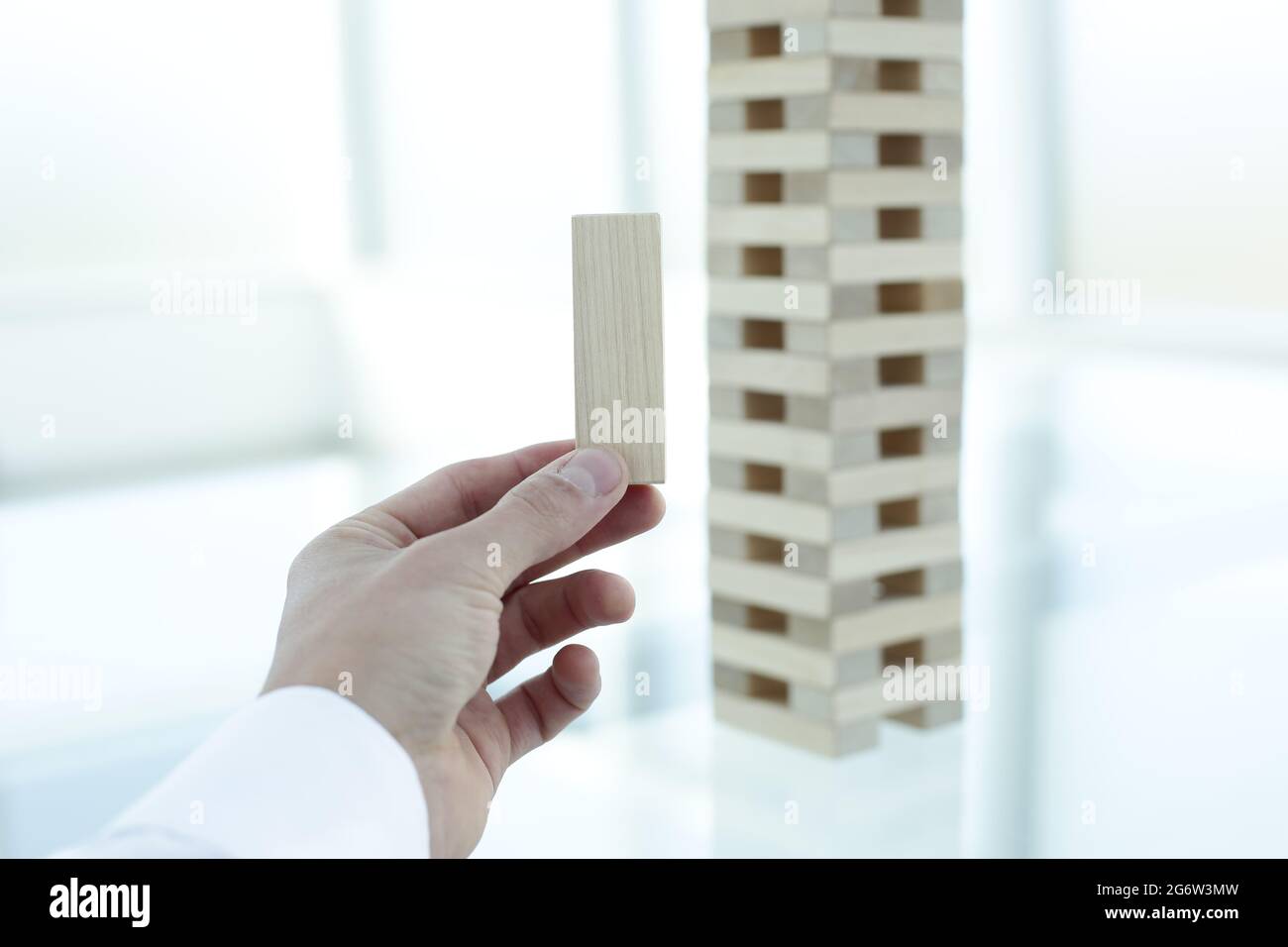 Man holds in hand one wooden piece of Jenga board game Stock Photo - Alamy