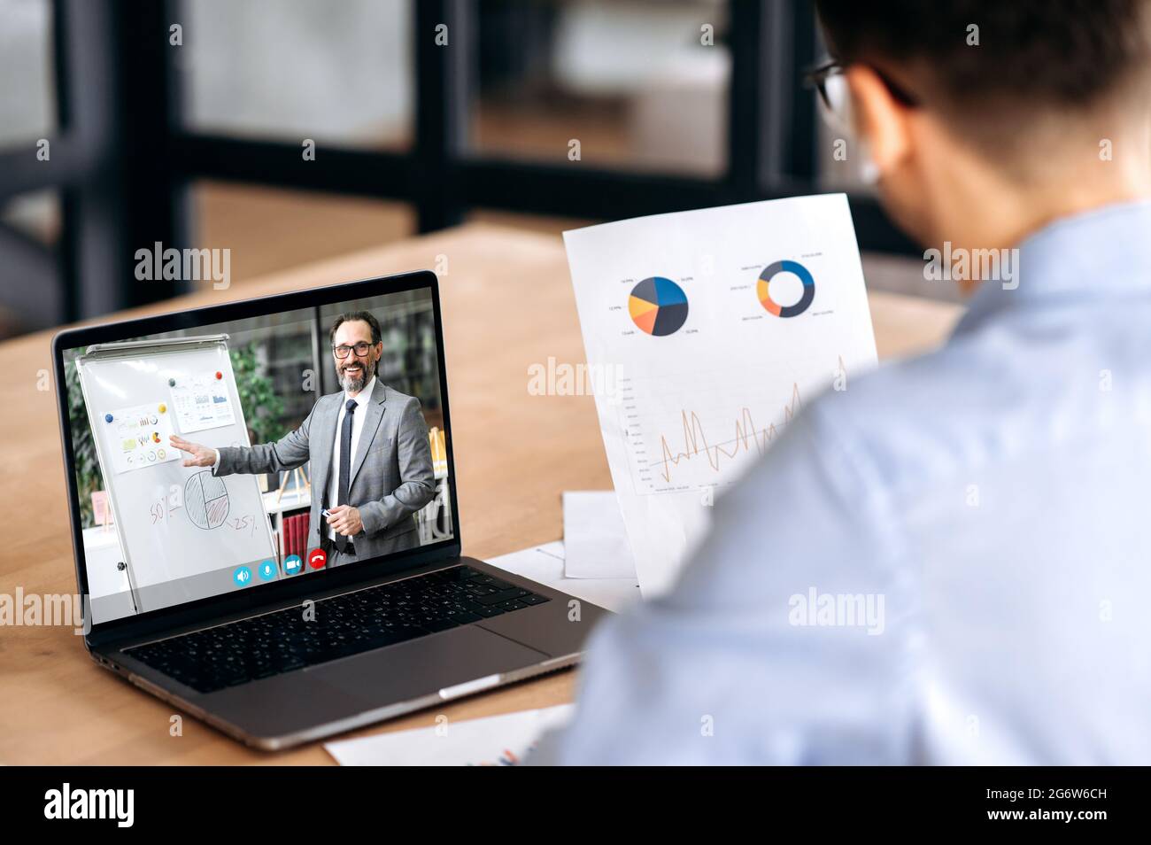 Over shoulder view of a caucasian male manager holding financial graphs ...