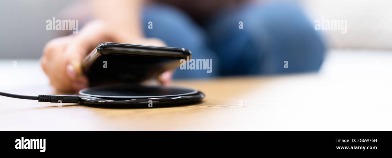 Wireless Phone Charger. Woman Using Smartphone Charge Stock Photo - Alamy