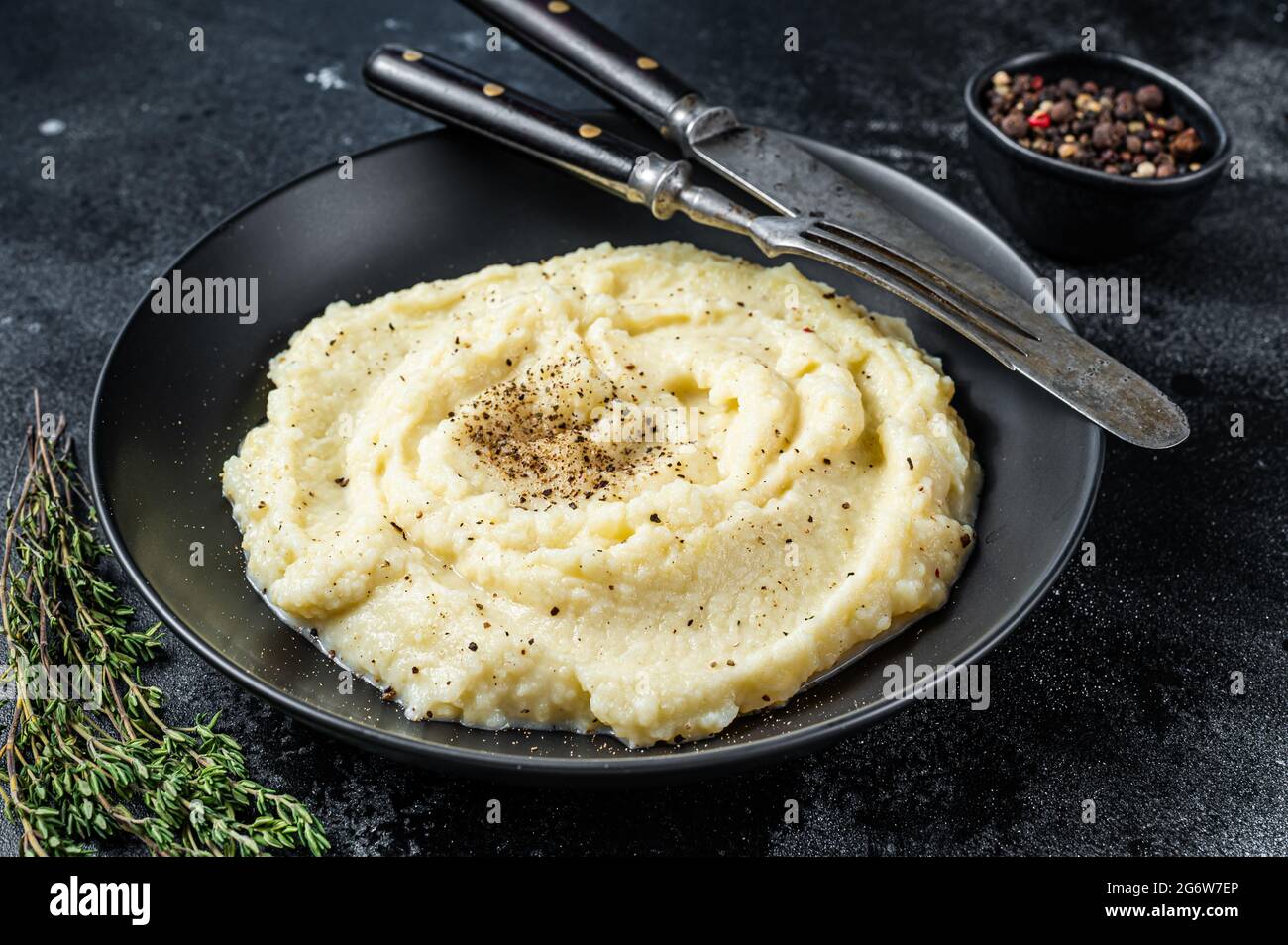 Potato puree, Mashed potatoes in a plate with herbs. Black background ...