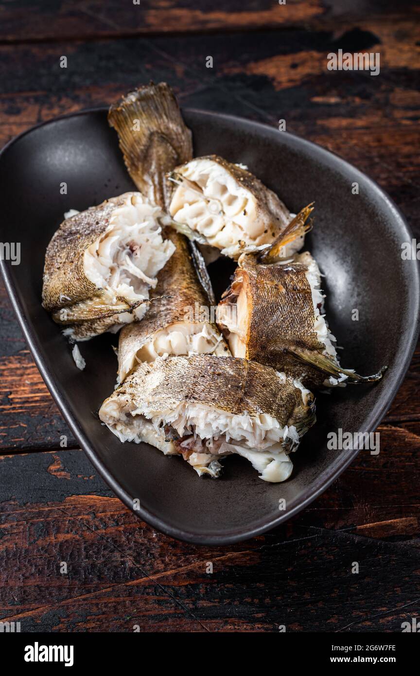 Roasted hake white fish in a plate. Dark wooden background. Top view ...