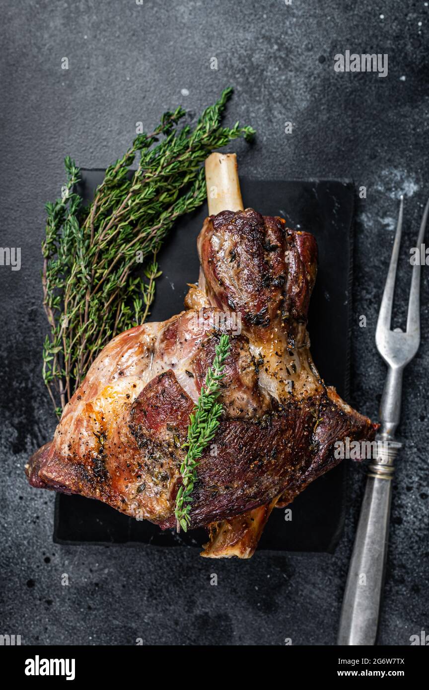 Oven Roasted lamb mutton whole leg with thyme. Black background. Top ...