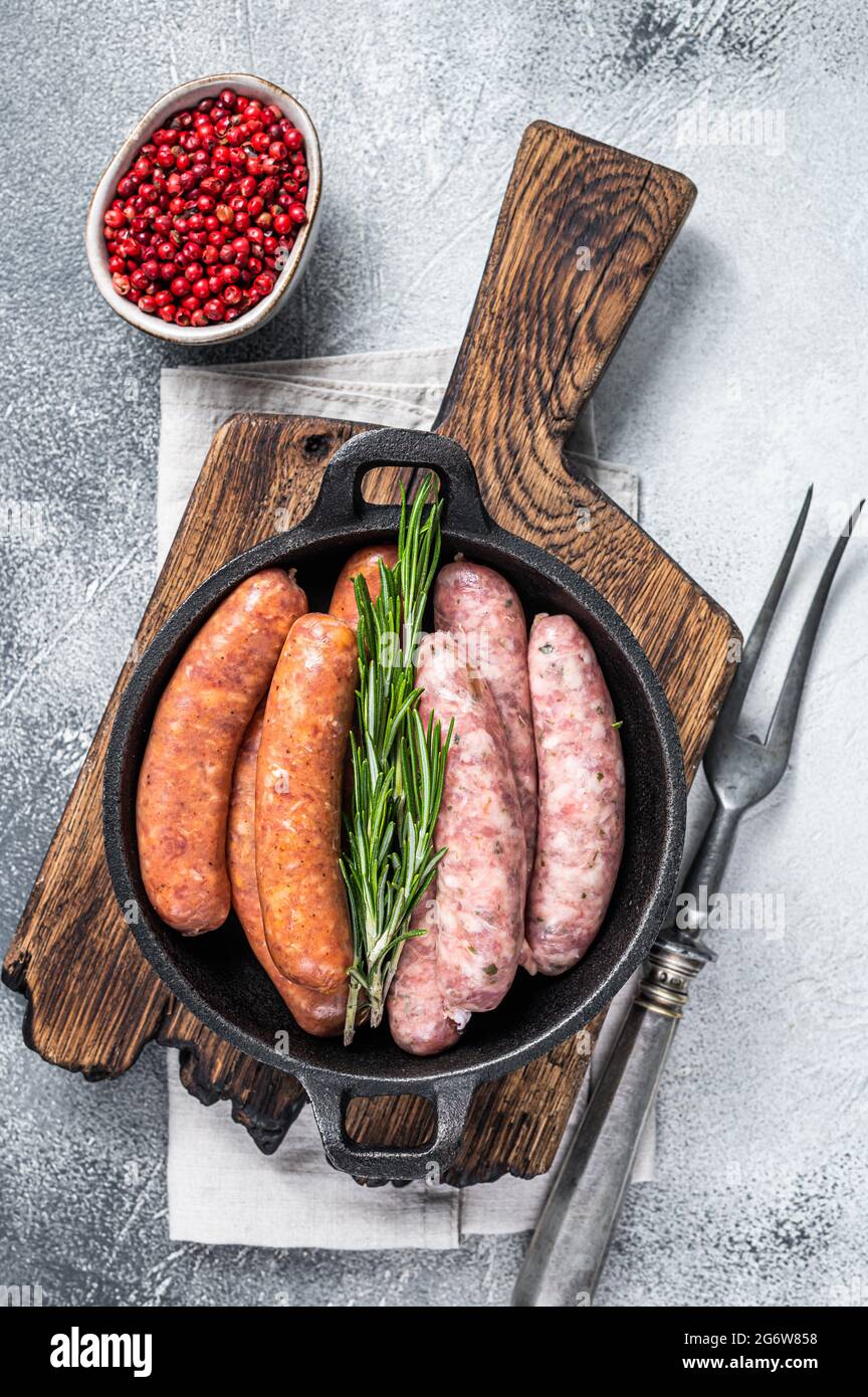 Assorted Raw sausages Chorizo and Bratwurst with spices in a pan with ...