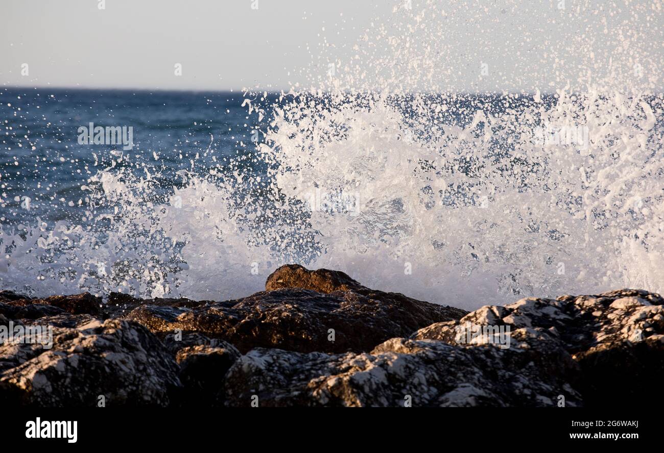Waves splashed over rocks on a very windy day at sunset (golden hour ...