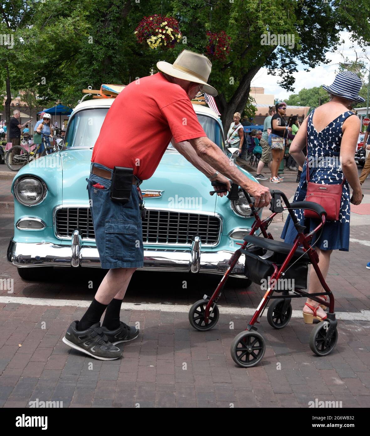 An elderly man using a wheeled rollator upright walker visits a classic ...