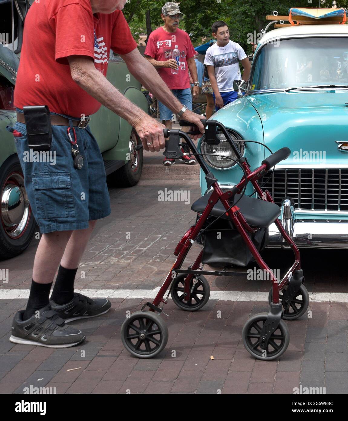 An elderly man using a wheeled rollator upright walker visits a classic ...