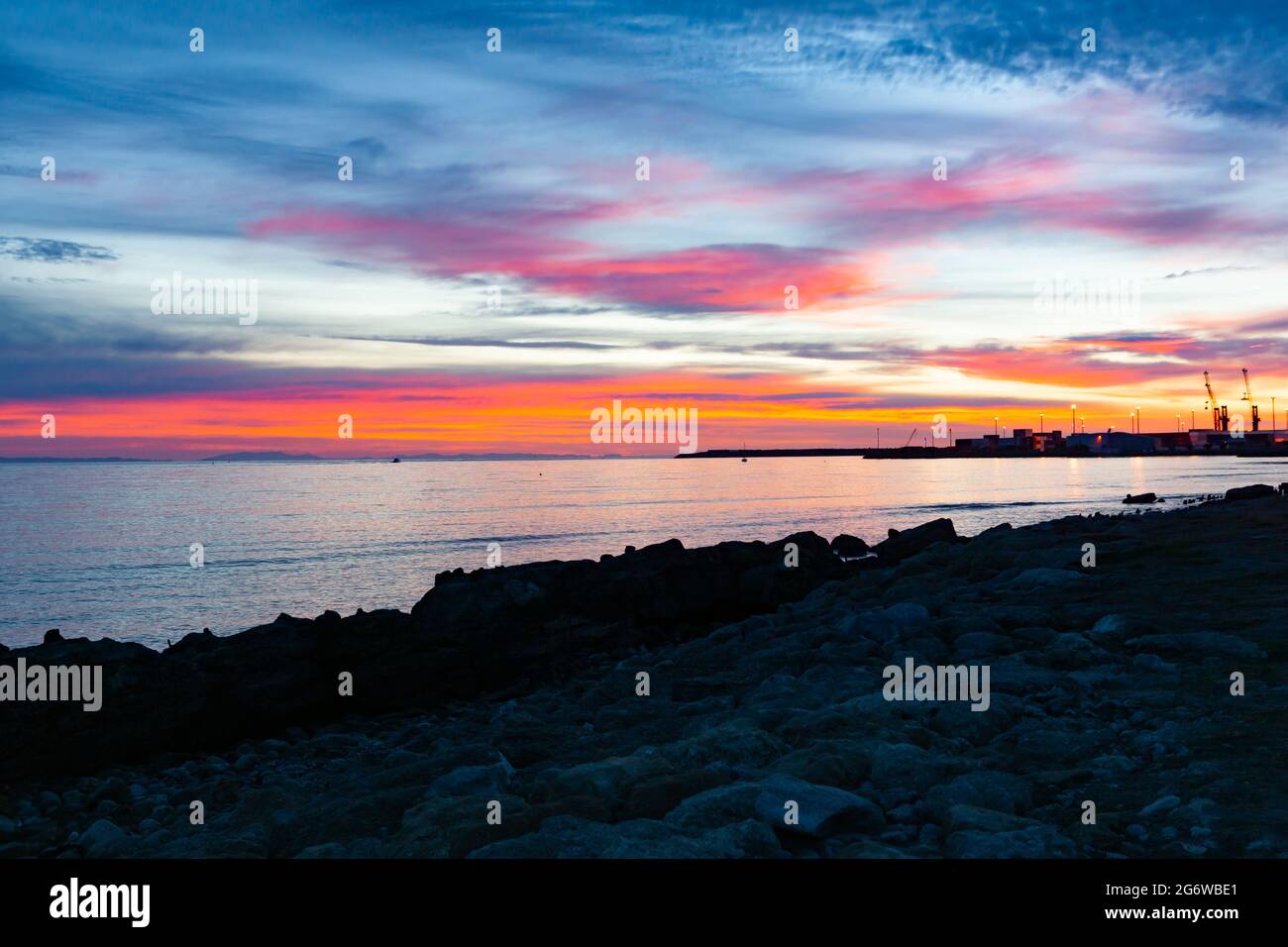 Coastal waterfront leading to distant port facility and cranes on ...