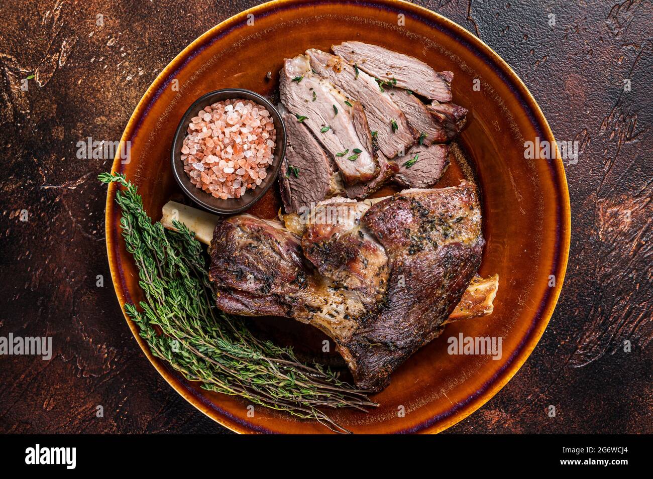 BBQ Roast Lamb mutton leg sliced on a rustic plate. Dark background ...
