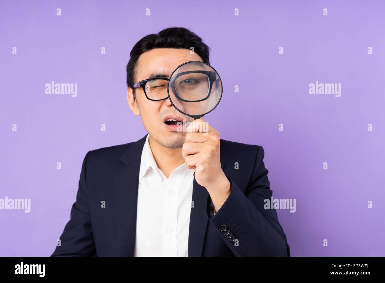 Business man in suit wearing magnifying glass, isolated on purple ...
