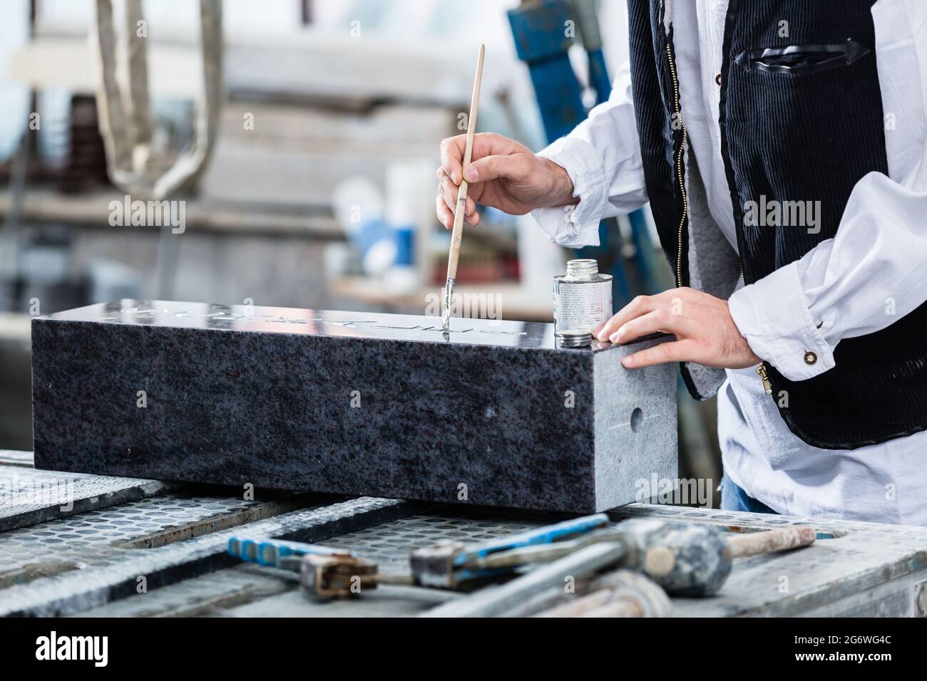 Stonemason painting in engraving with silver paint and brush Stock ...