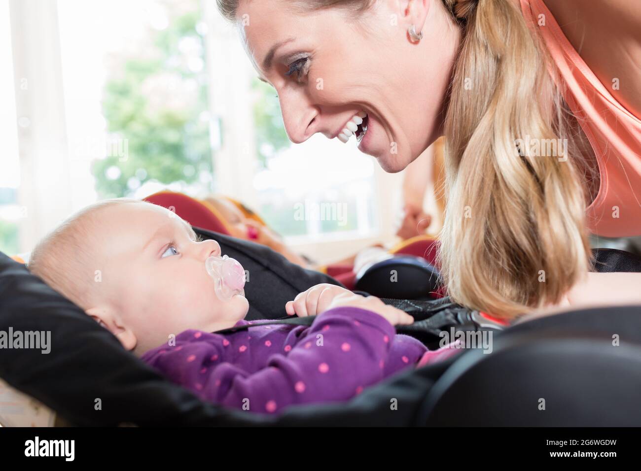 Moms and babies in mother and child course practicing with baby seats ...