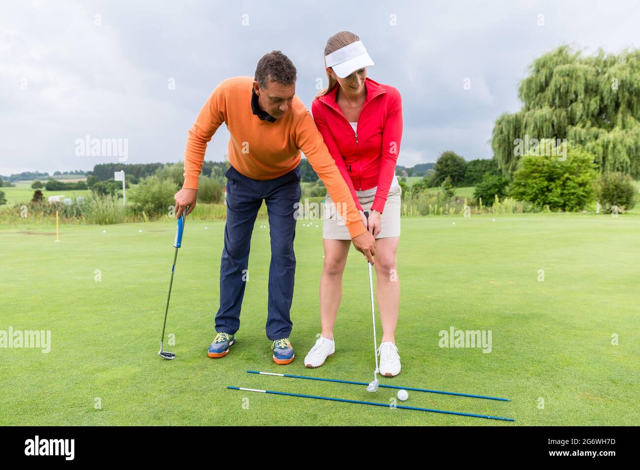 Young female golf player at driving range with a golf coach Stock Photo ...
