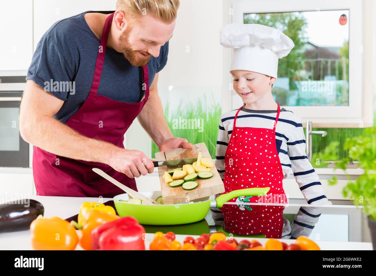 Happy father and son preparing food together in kitchen Stock Photo - Alamy