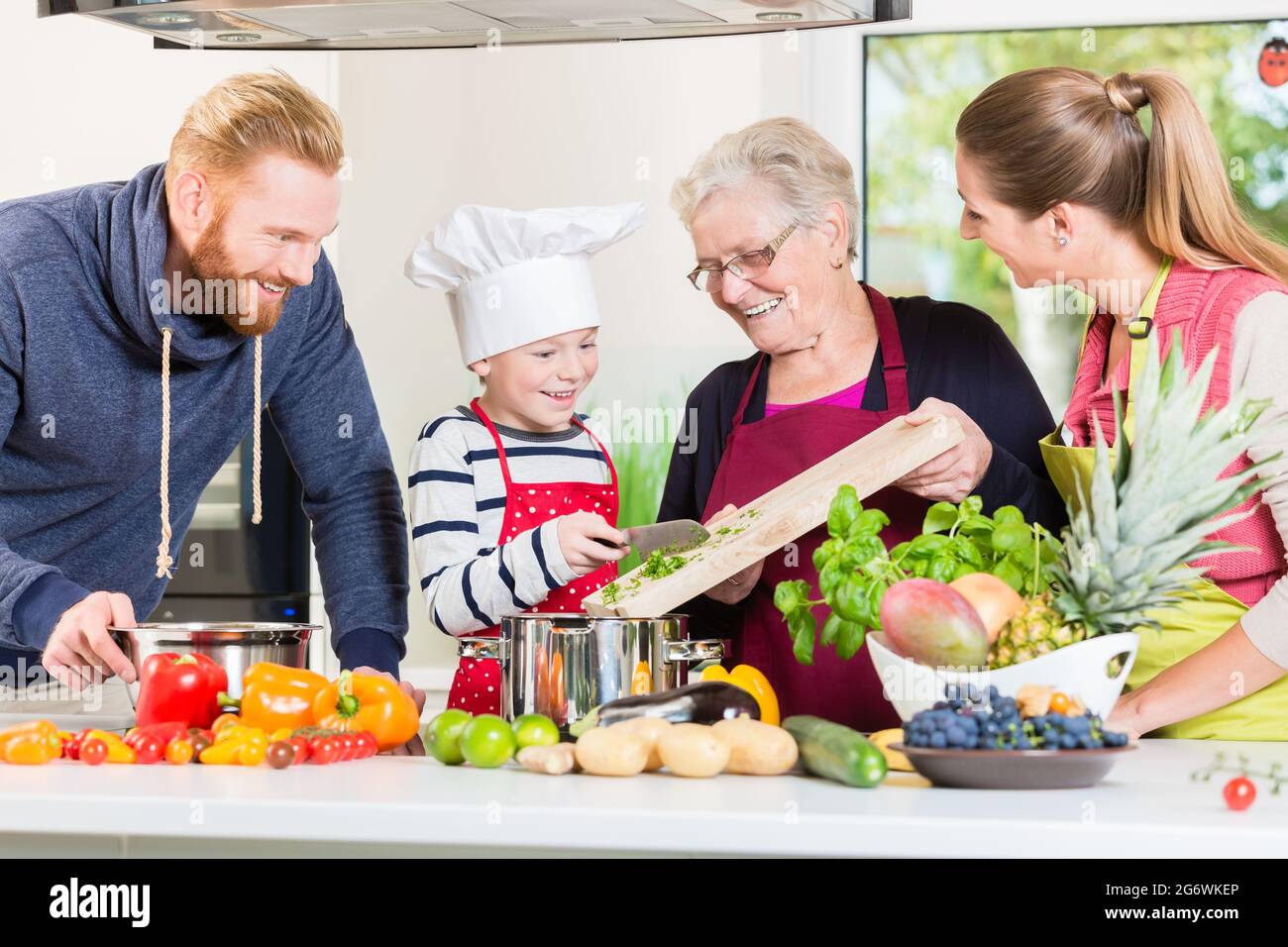 Family cooking in multigenerational household with son, mother, father ...