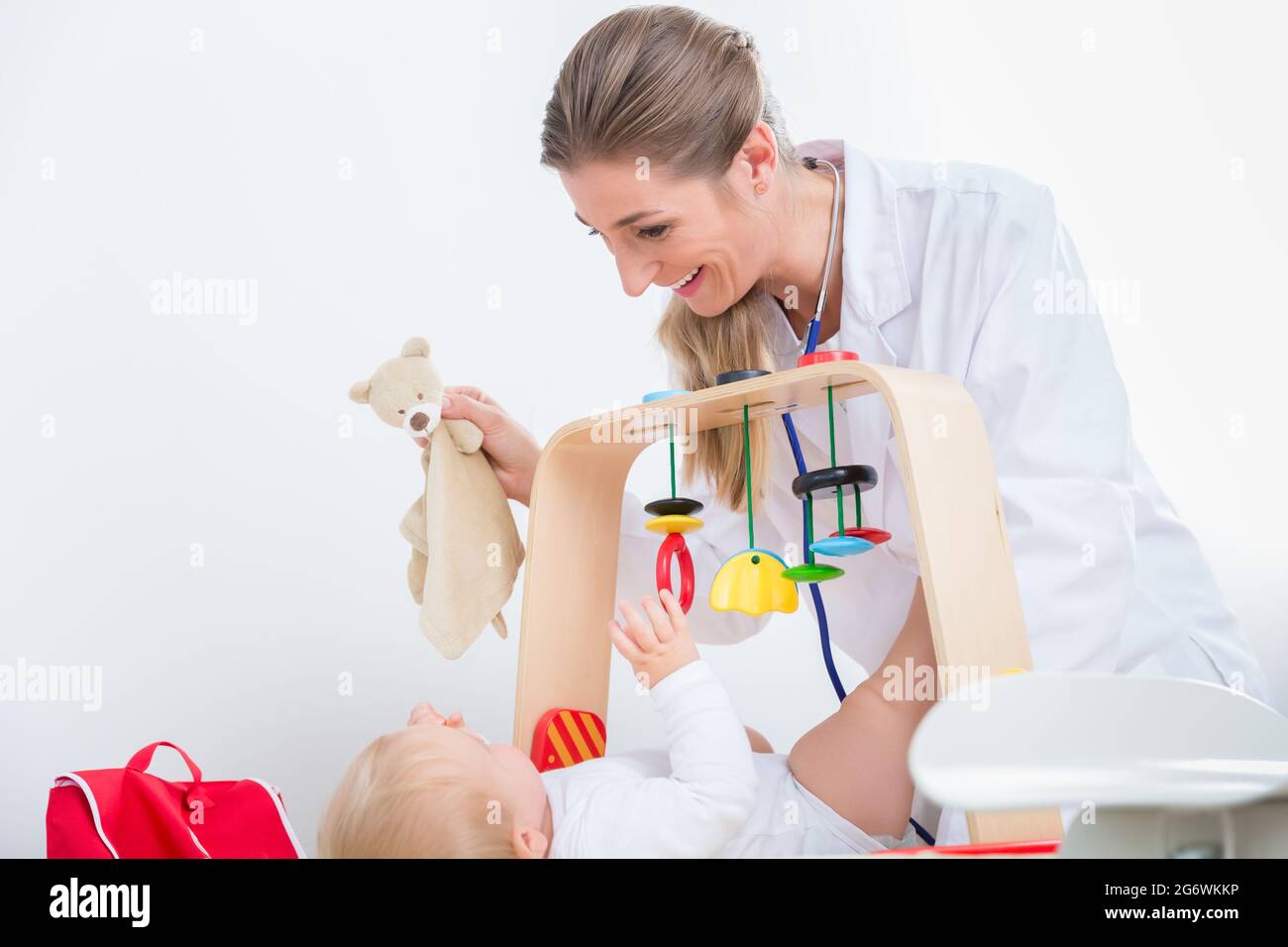 Dedicated female pediatrician smiling while playing with a healthy and ...