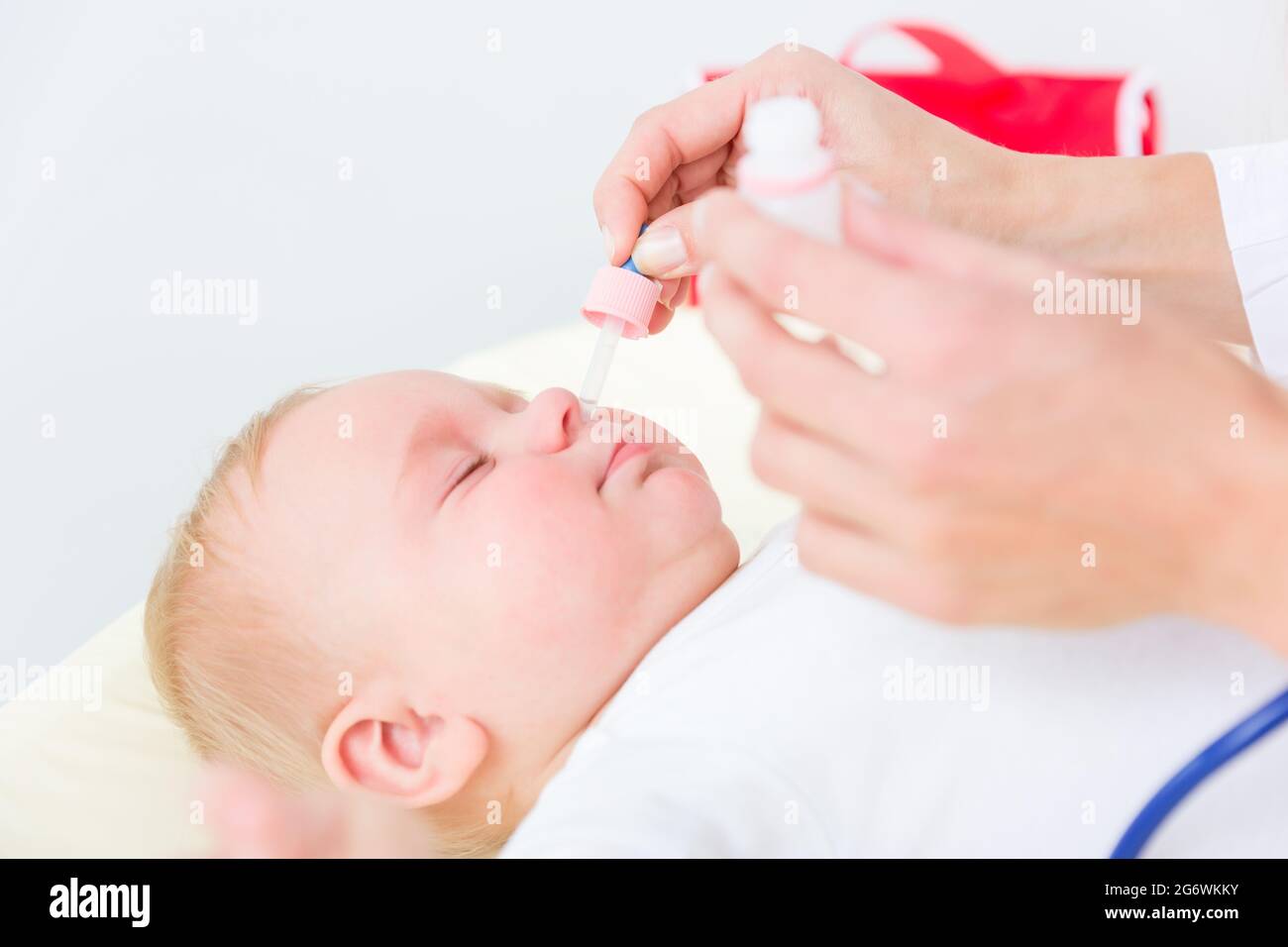 Close-up of the hands of a pediatrician clearing the nose of a baby, by ...
