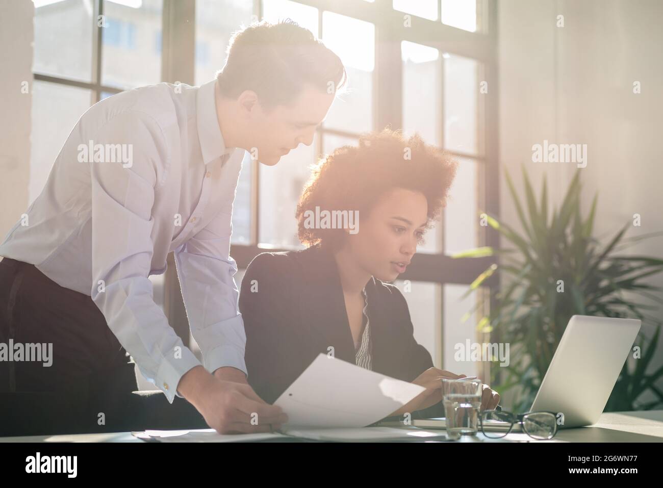 Skilled business man helping his colleague while working on laptop in ...
