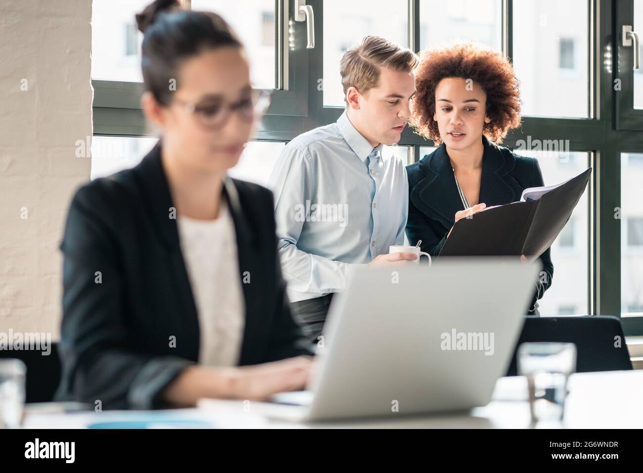 Two young malicious employees gossiping about their hard-working ...