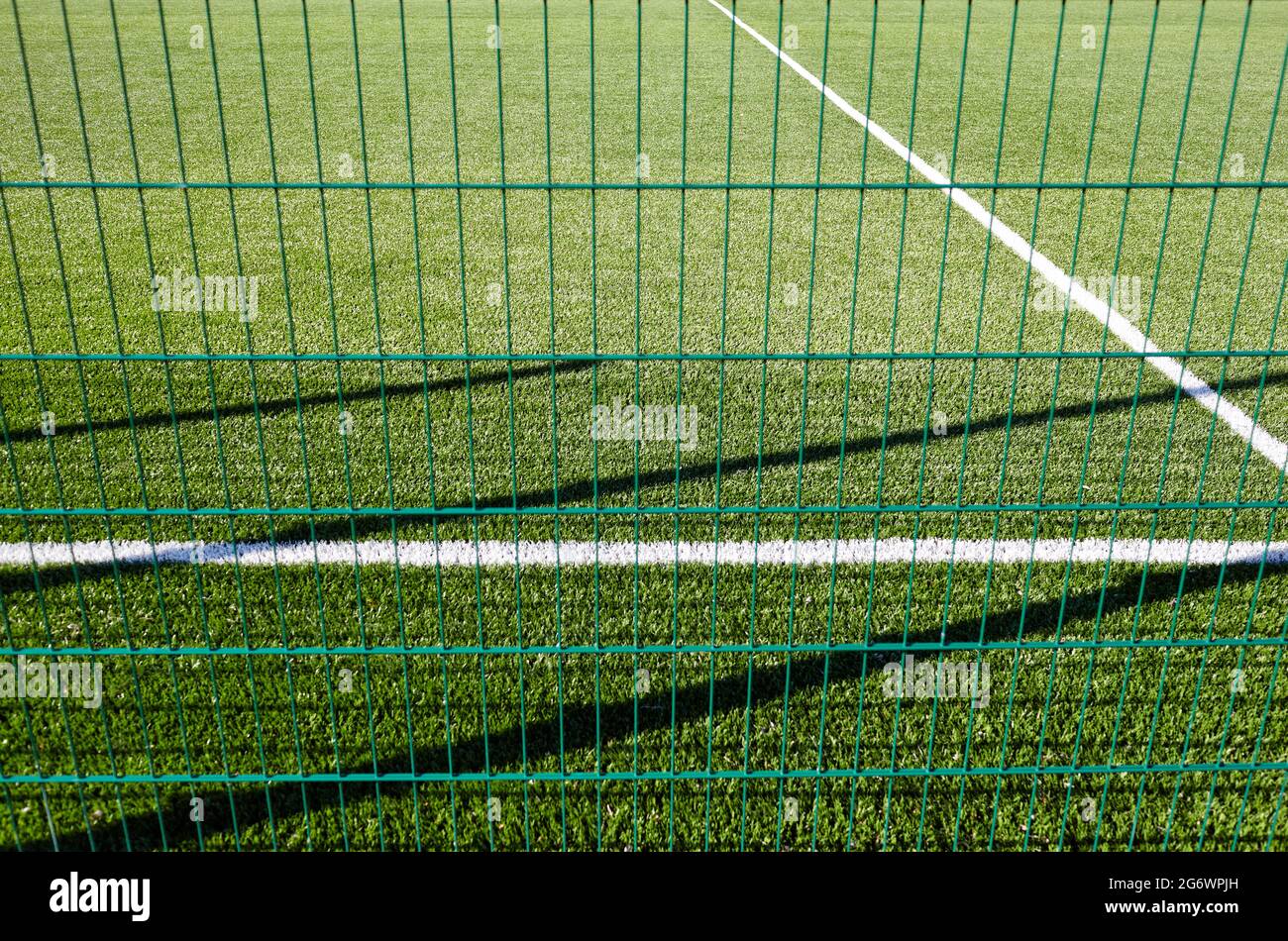 Lawn field for playing football behind the green fence mesh. Close-up ...