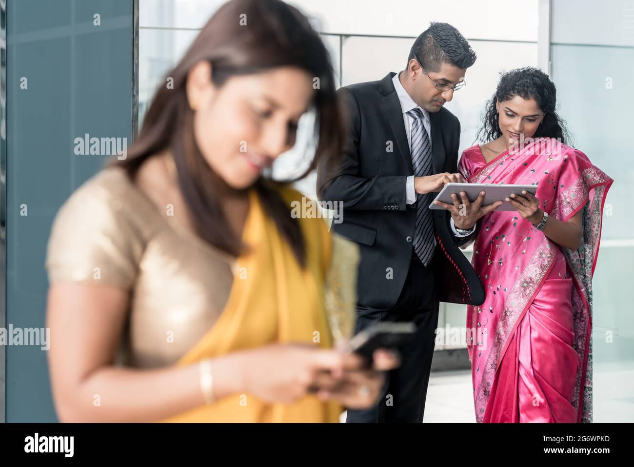 Three Indian business people using modern devices connected to the ...