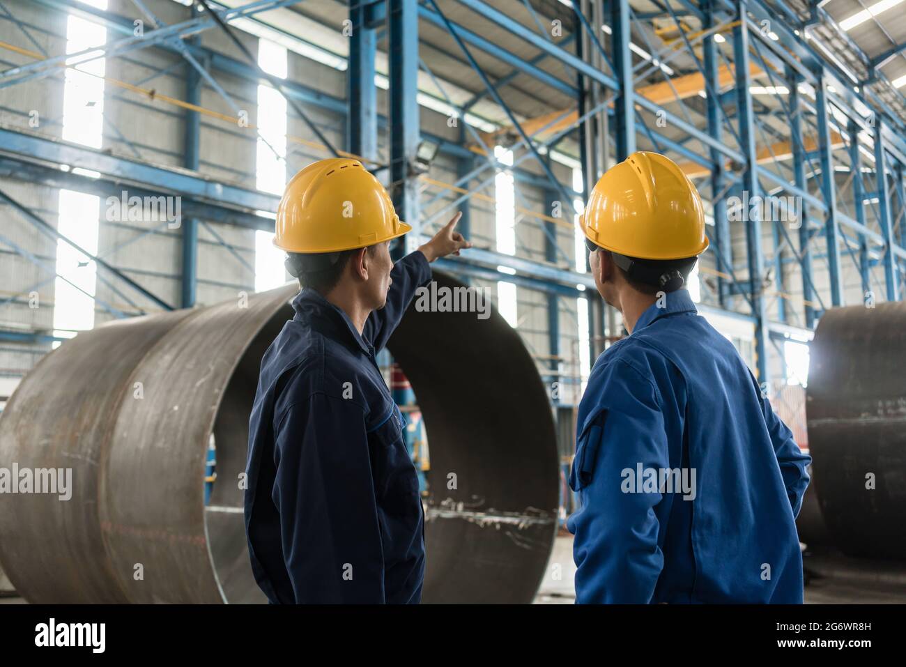 Skilled worker pointing up while giving instructions to an apprentice ...