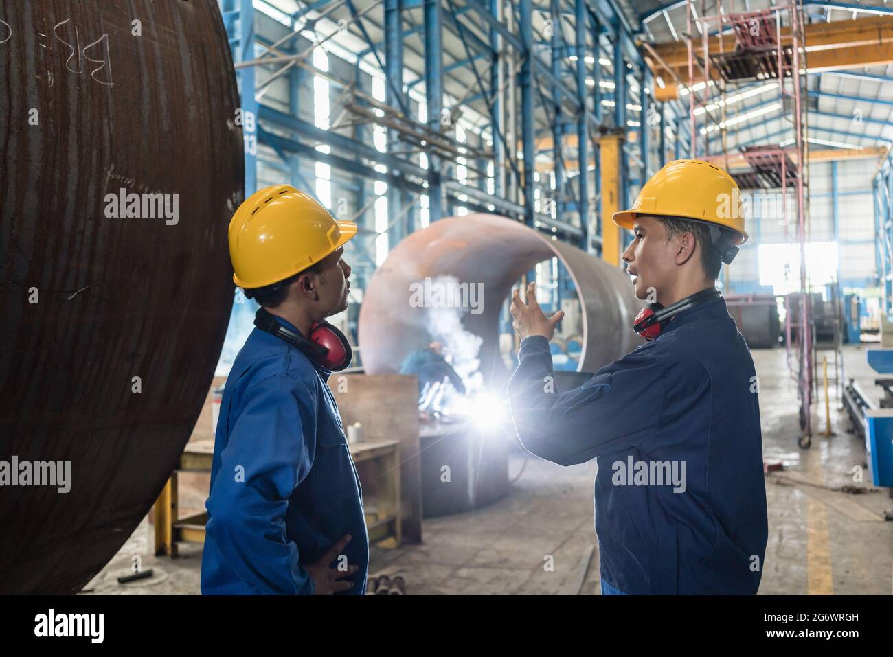 Two Asian experts talking while supervising the fabrication of ...
