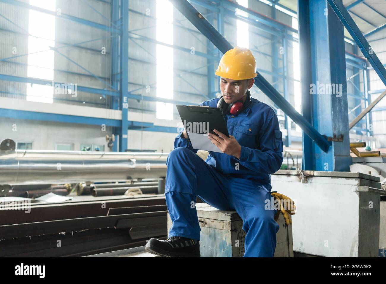 Determined Asian worker writing observations about the manufacturing ...