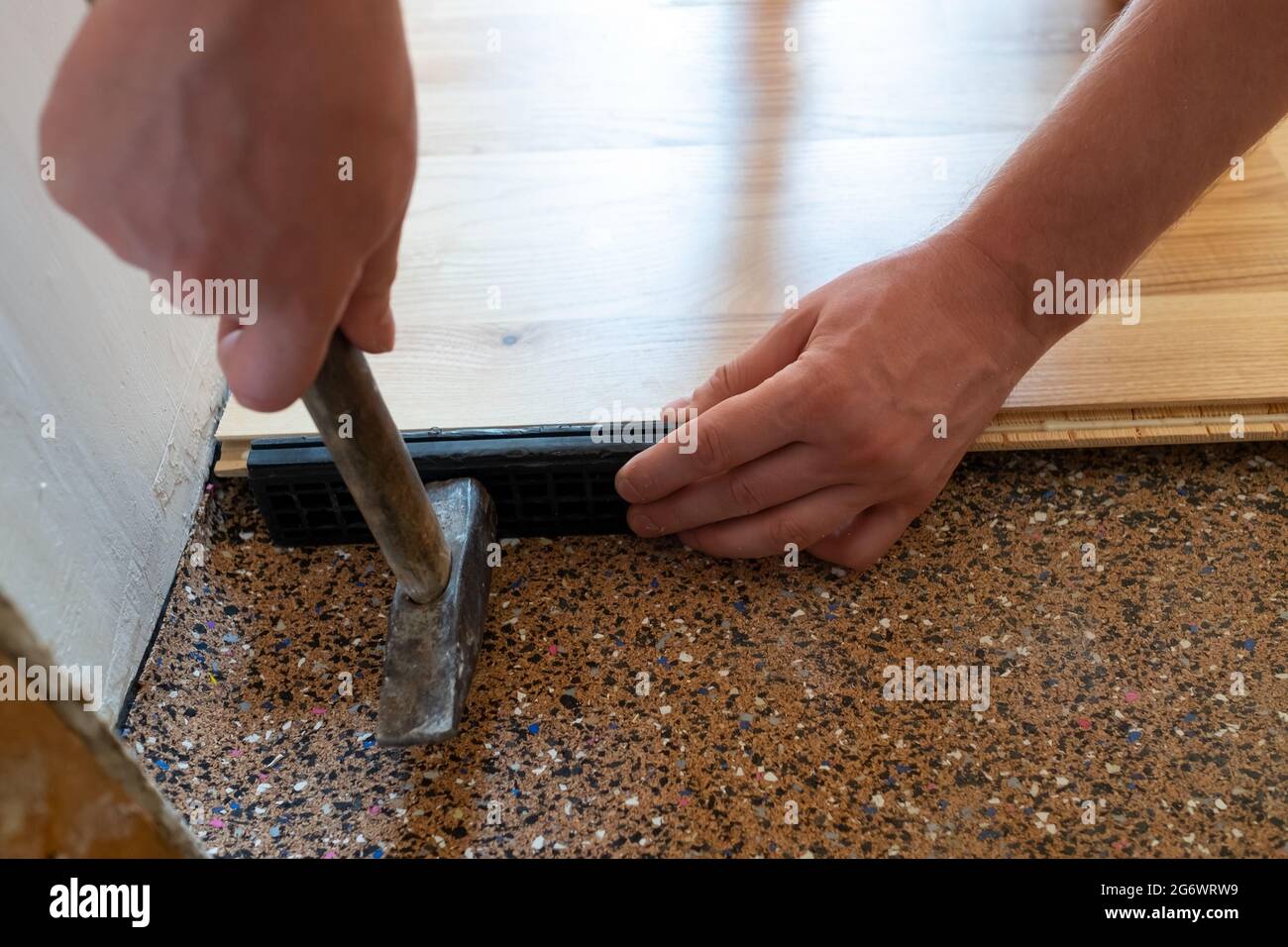 Worker installing wood parquet board during flooring work with hammer ...