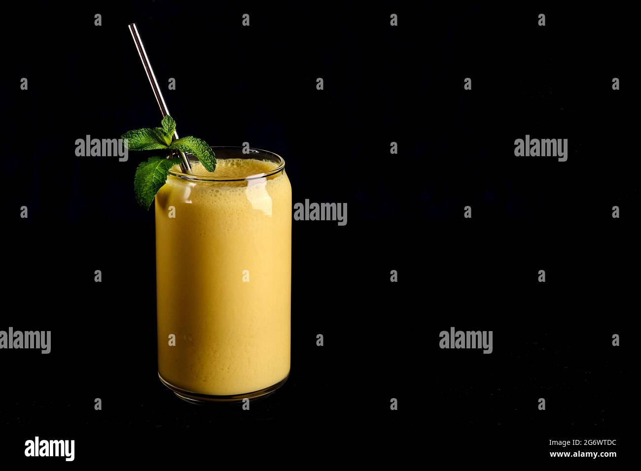 Mango lassi in glass with tube on black background. Traditional Indian ...